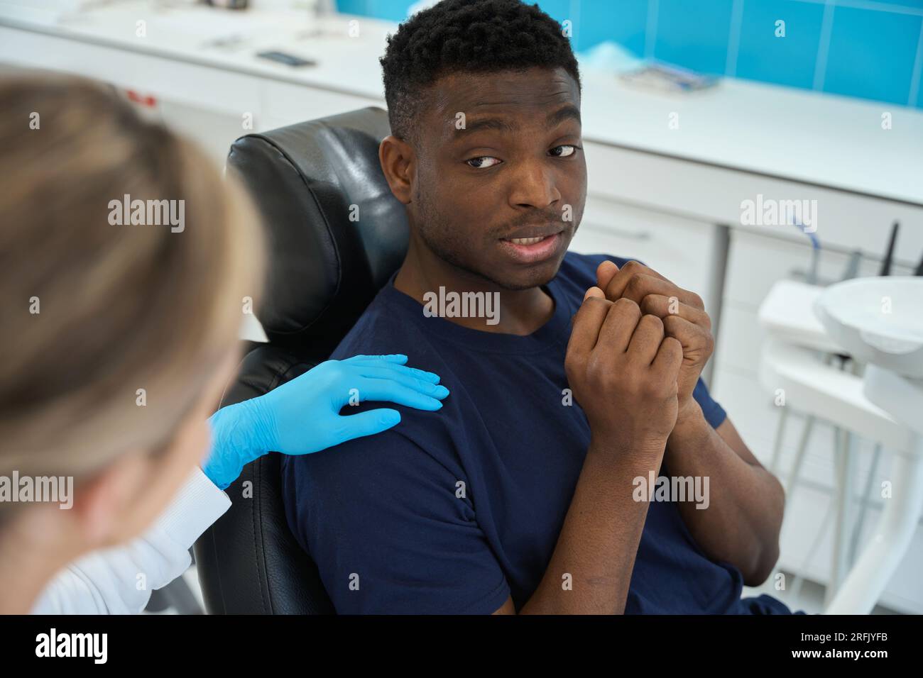 Scared male patient sitting in orthodontic chair and asking female ...