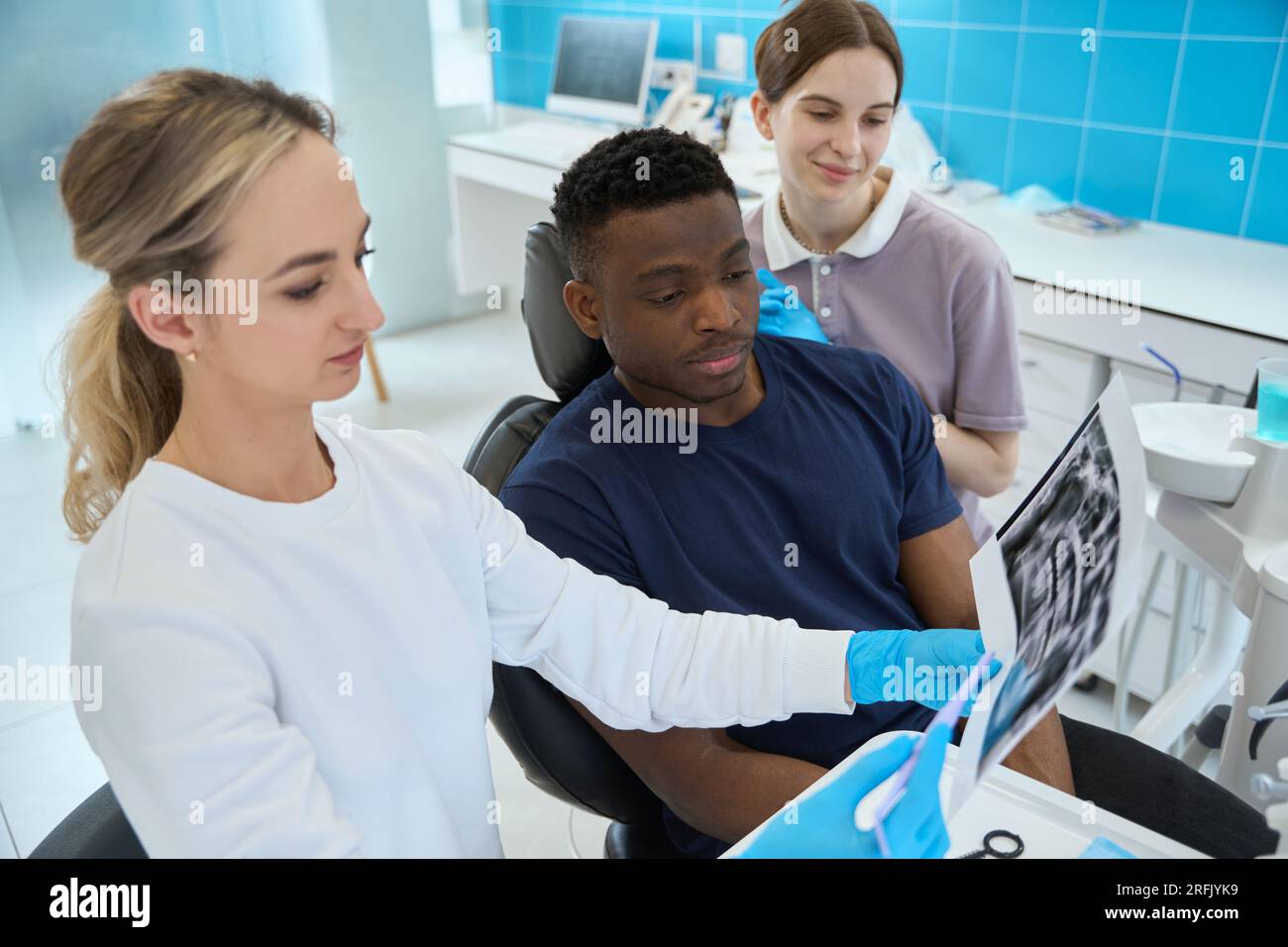 Focused woman stomatologist looking at x-ray image of male client ...