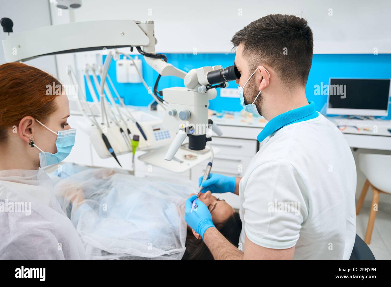 Male treats a patients tooth under a microscope Stock Photo - Alamy