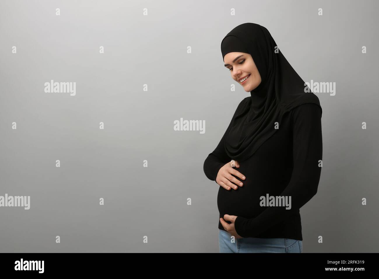 Portrait of pregnant Muslim woman in hijab on light gray background ...