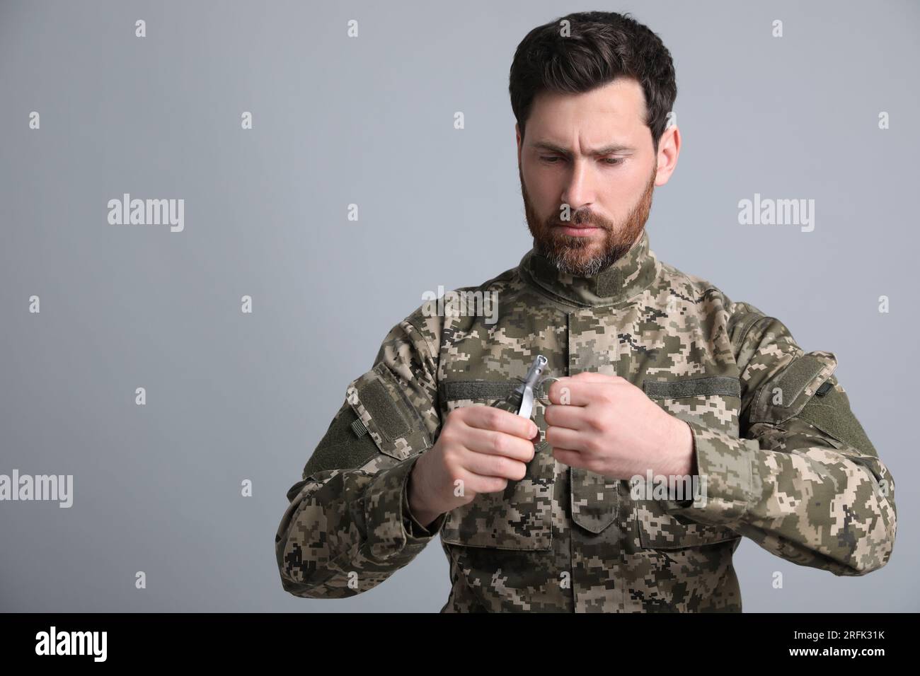 Soldier pulling safety pin out of hand grenade on light grey background ...