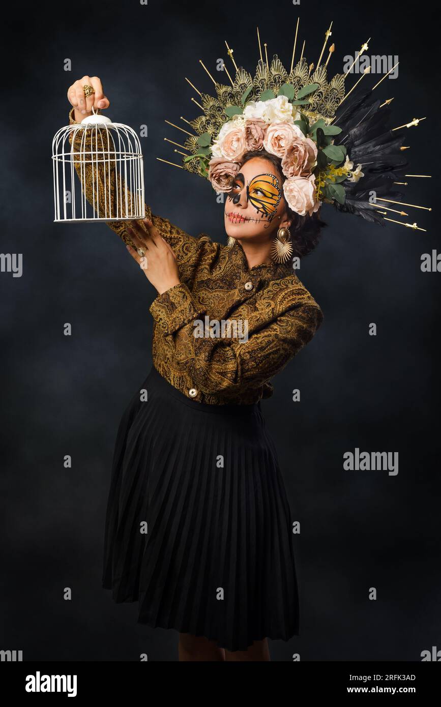 Portrait of woman in sugar skull makeup holding a cage . Halloween and ...
