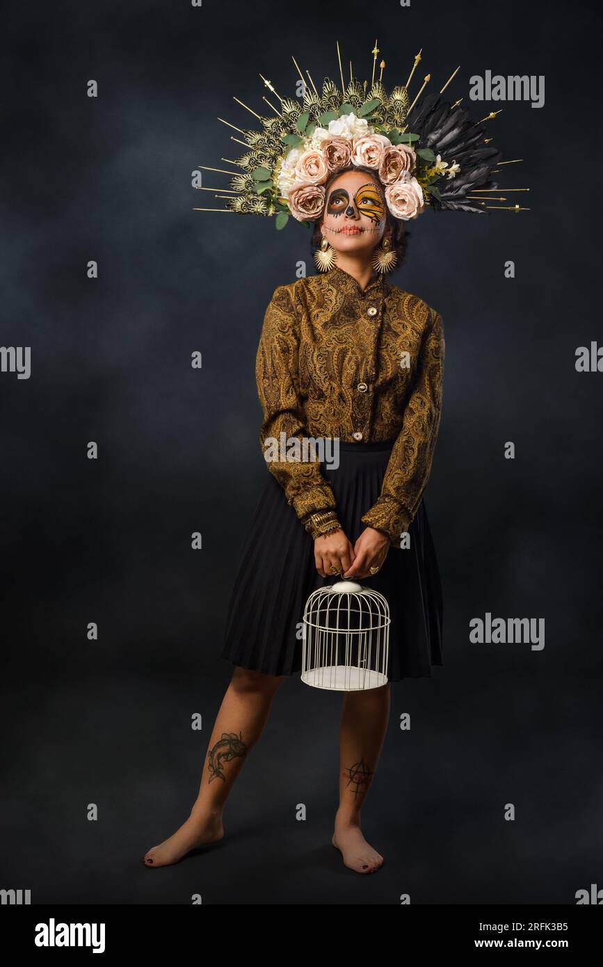 Portrait of woman in sugar skull makeup holding a cage . Halloween and ...