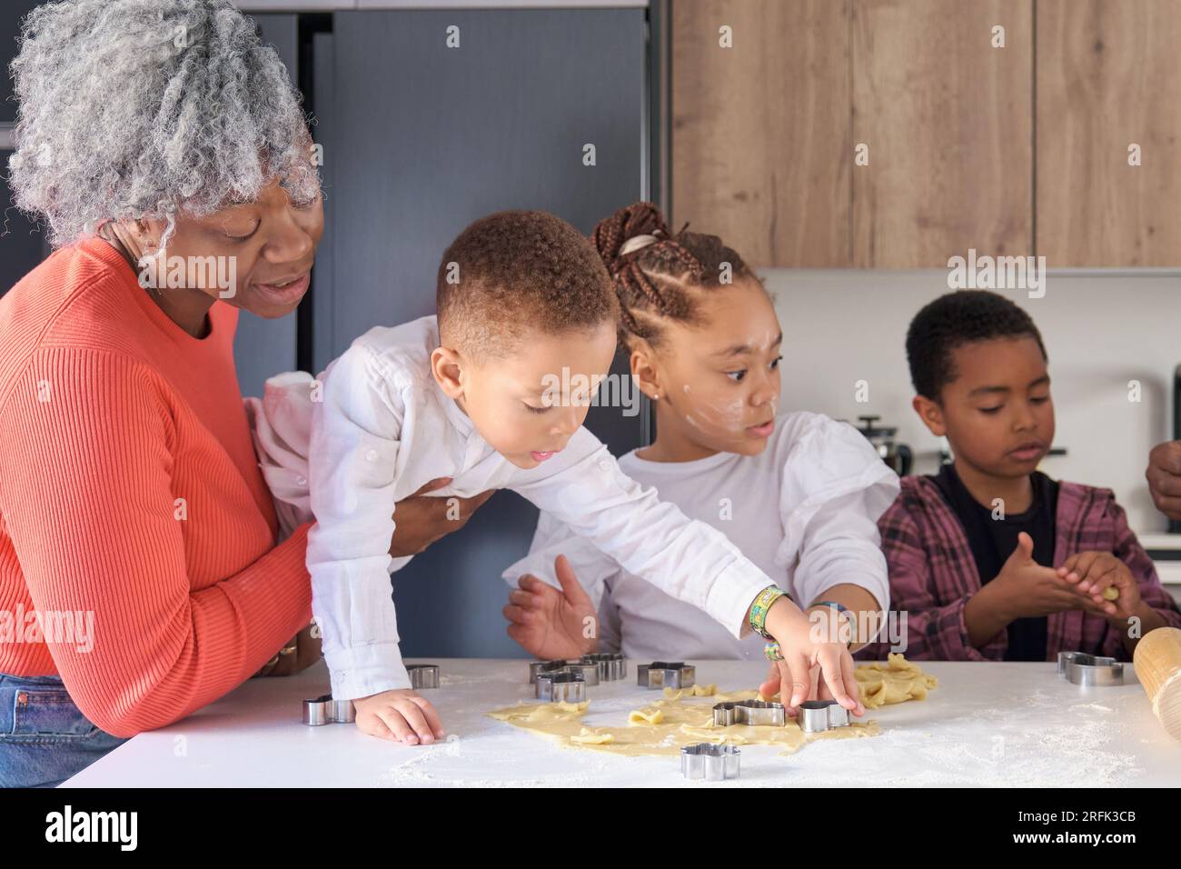 African family cutting cookie shapes in a cookie dough in the kitchen ...