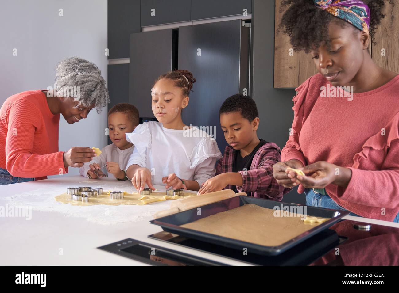 African family cutting cookie shapes in a cookie dough in the kitchen ...