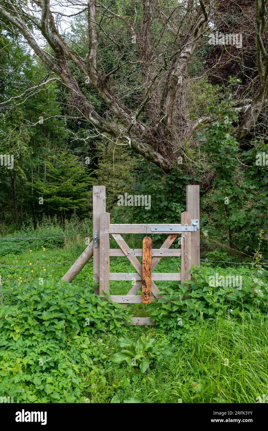 Wooden gate with private carved on it and barbed wire fence, overgrown ...