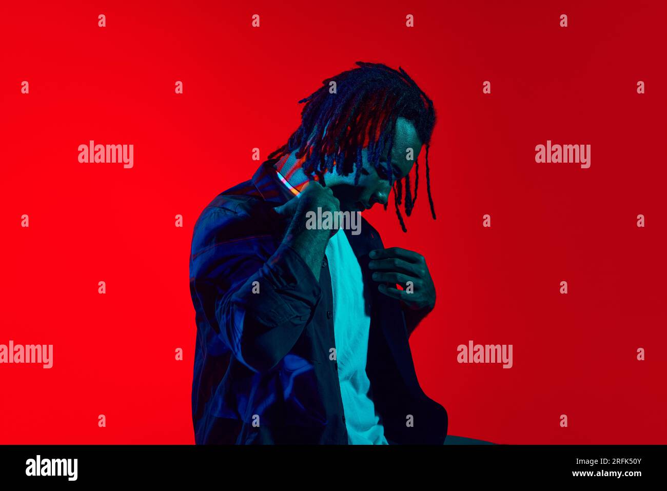 Musician. Handsome, stylish young guy with dreads posing against red ...