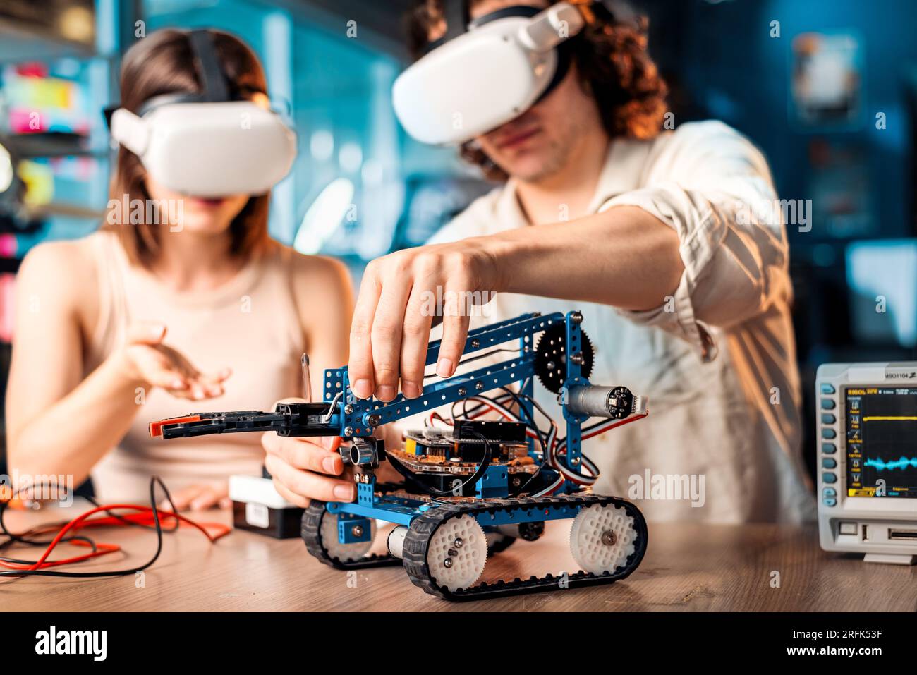 Young man and woman in VR glasses doing experiments in robotics in a ...