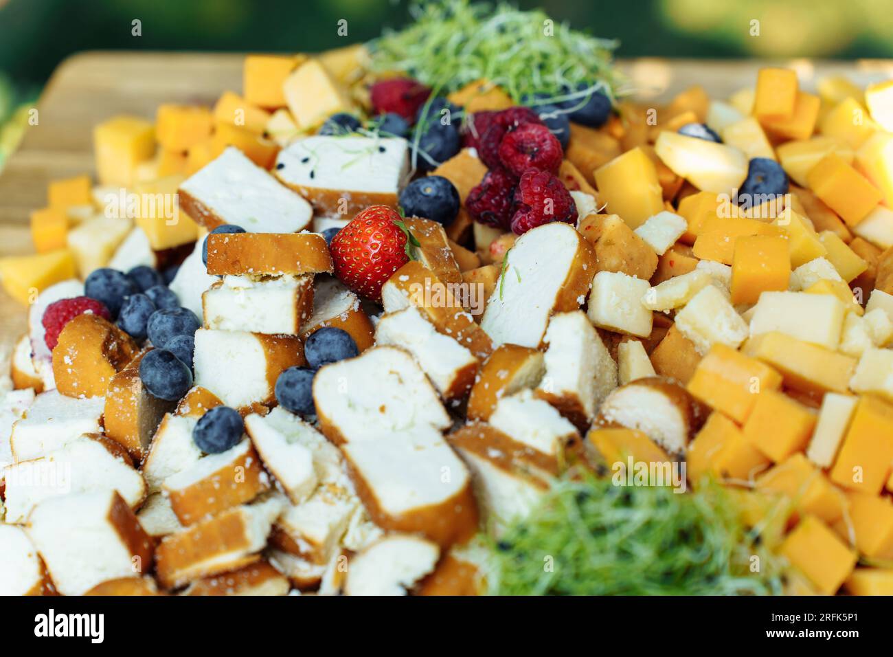 Board with sliced cheese, bread and berries for a festive buffet in the ...