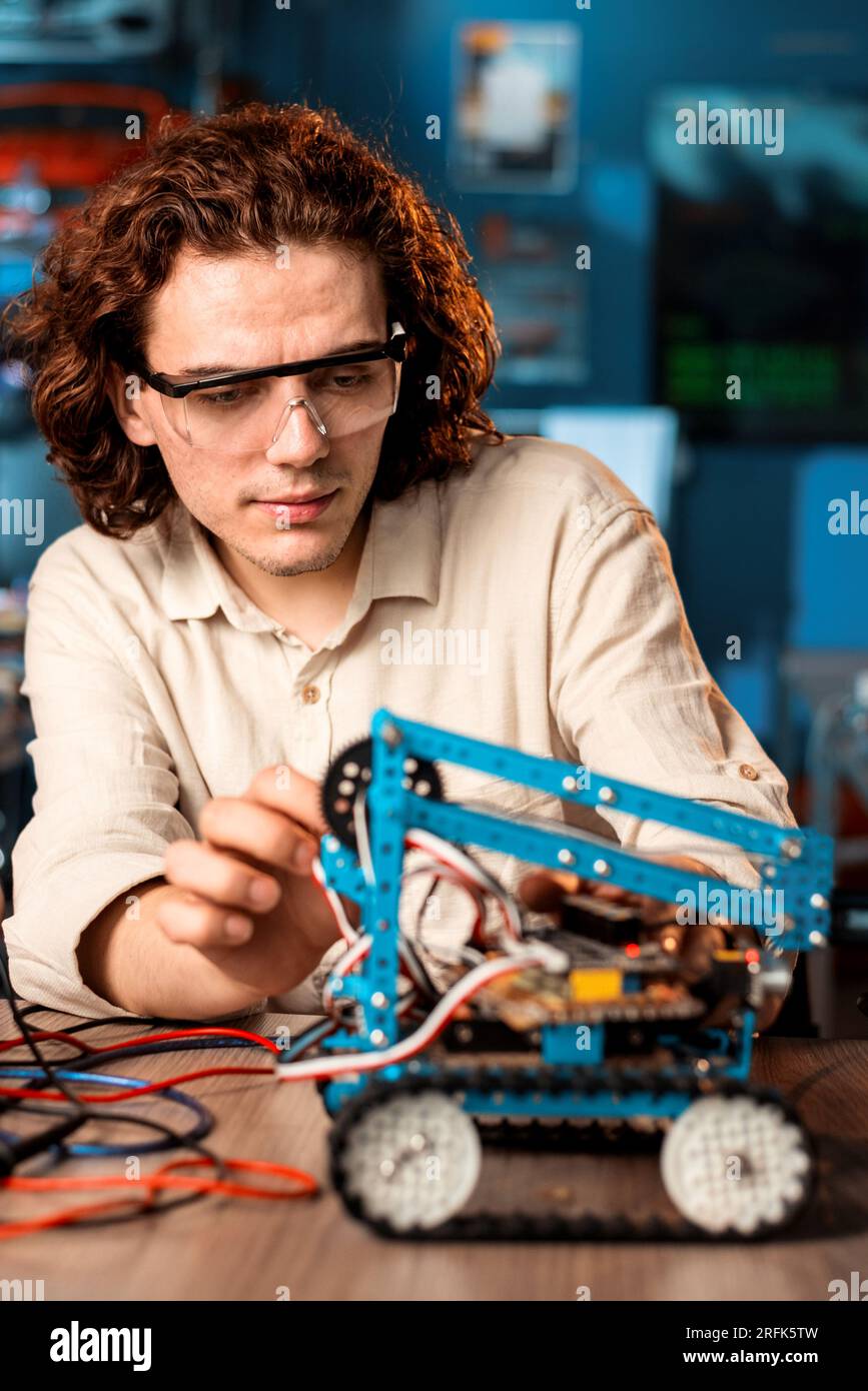 Young man in protective glasses doing experiments in robotics in a ...