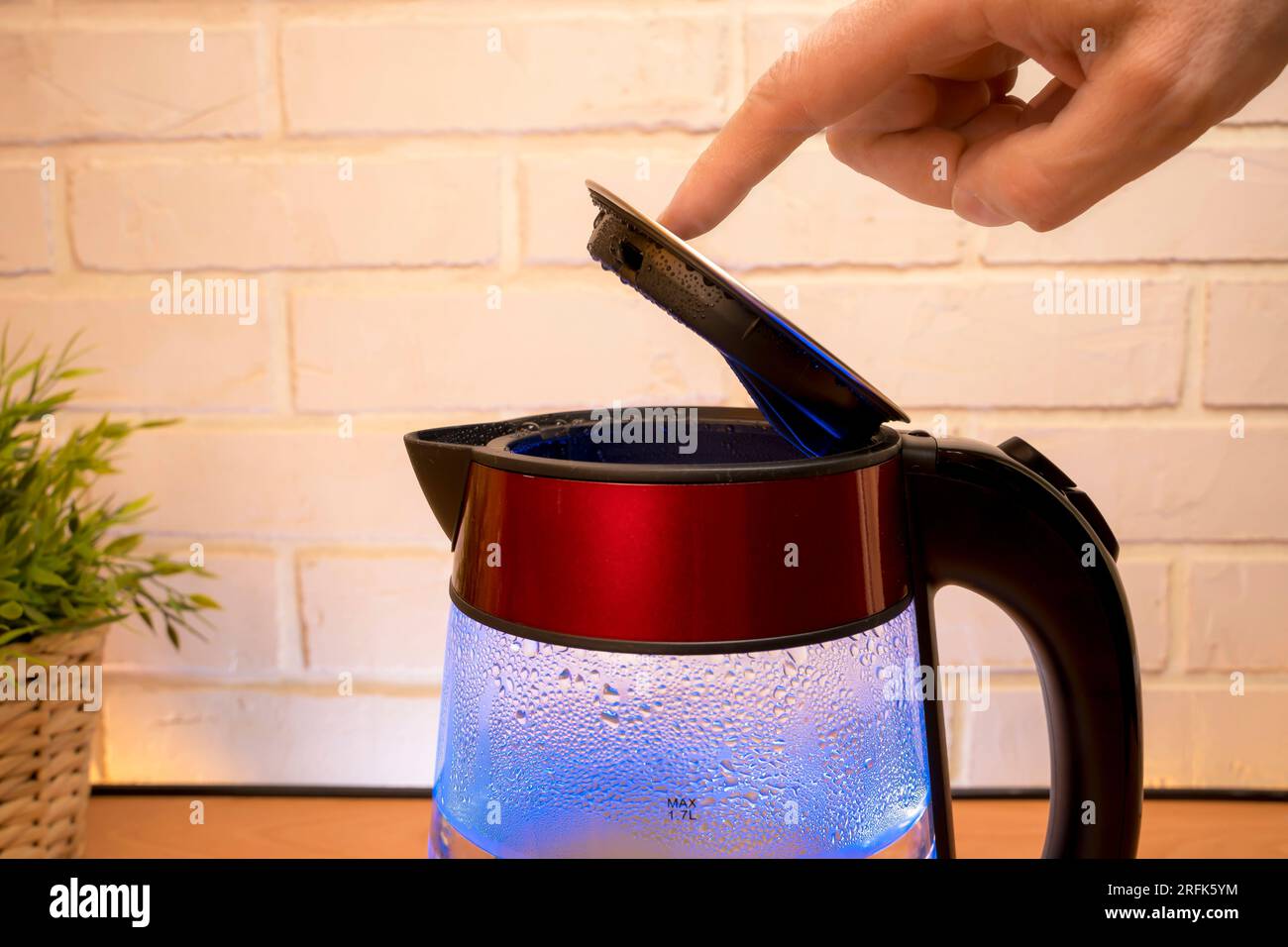 an electric kettle with boiling water and condensate on glass walls ...
