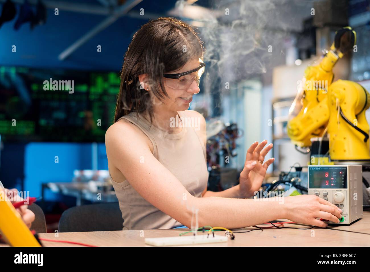 Young woman in protective glasses doing experiments with electricity in ...