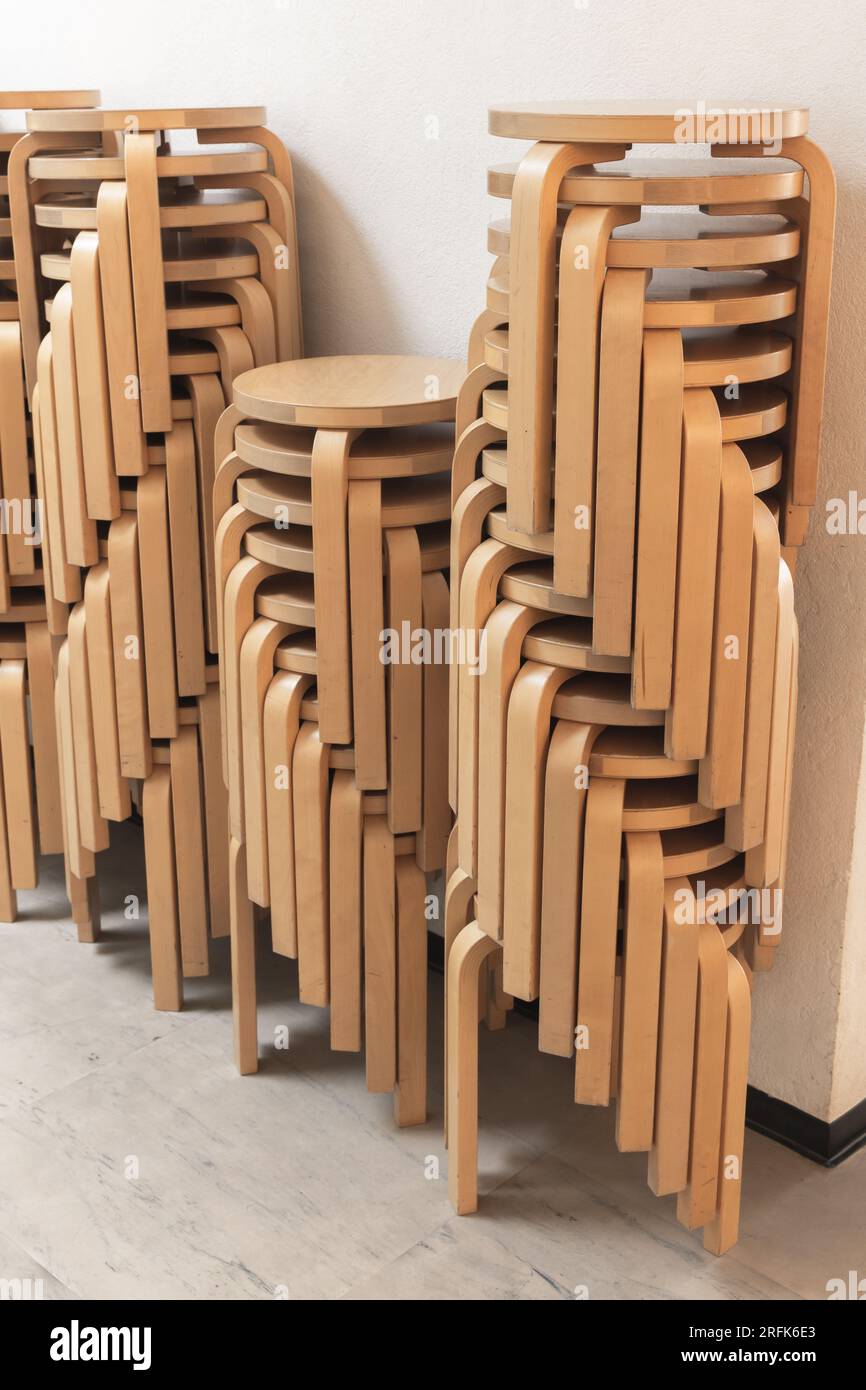 Stacked wooden stools made from bent plywood stand in front of a white ...