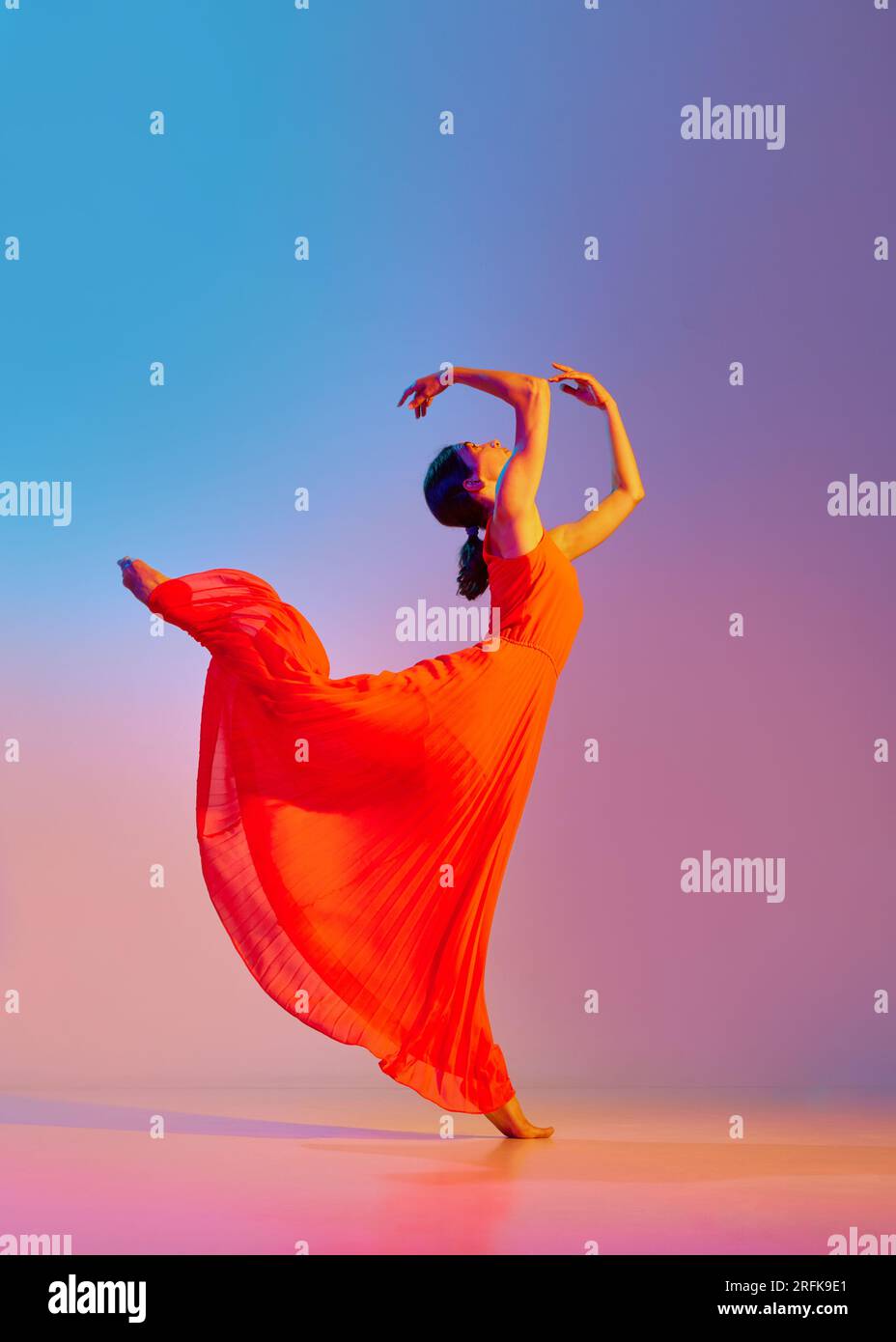 Elegant, graceful young woman dancing in red dress against gradient ...