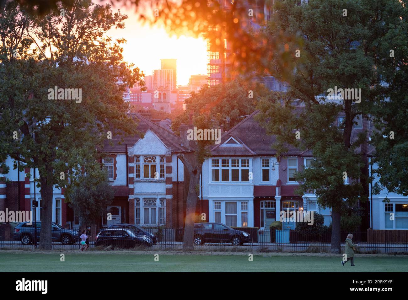 Orange glow from a setting summer sun which sinks below the skyline of ...