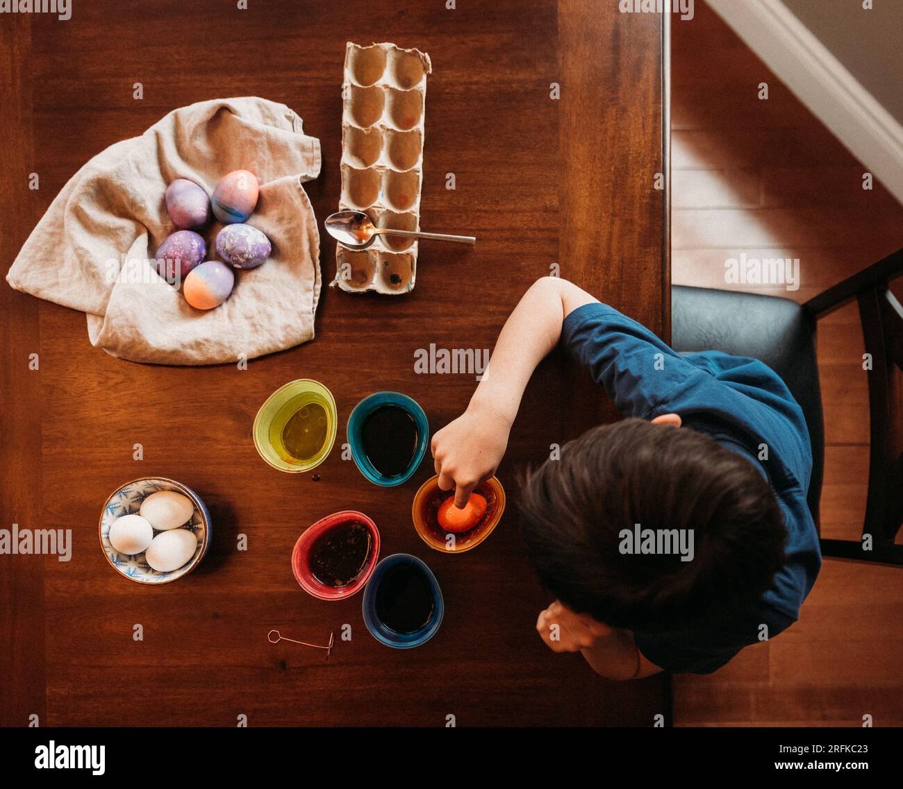 High angle shot of young boy dying easter eggs at a wooden table Stock ...