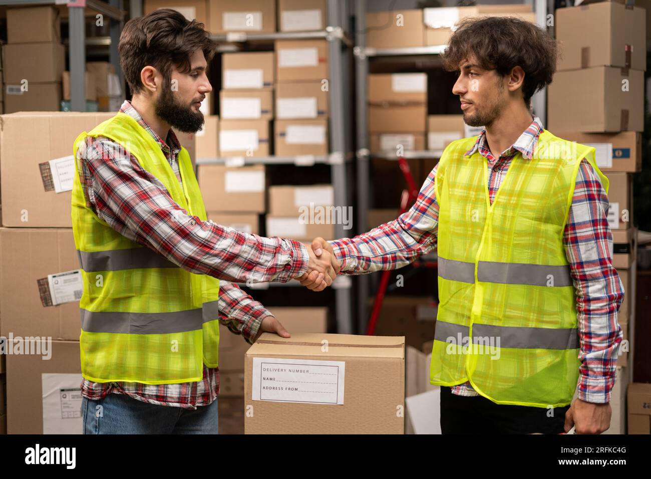 Multi-ethnic male staff shaking hands with each other in warehouse ...
