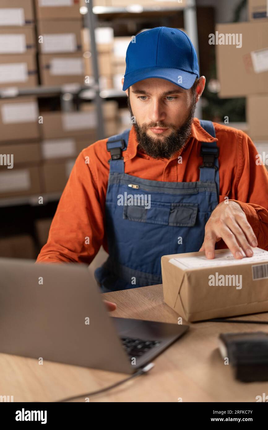 Warehouse male manager using laptop computer to check order number on a ...