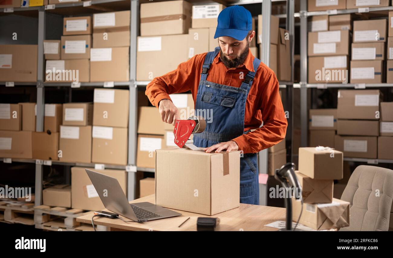 Warehouse male worker packing shipping ecommerce box checking website ...