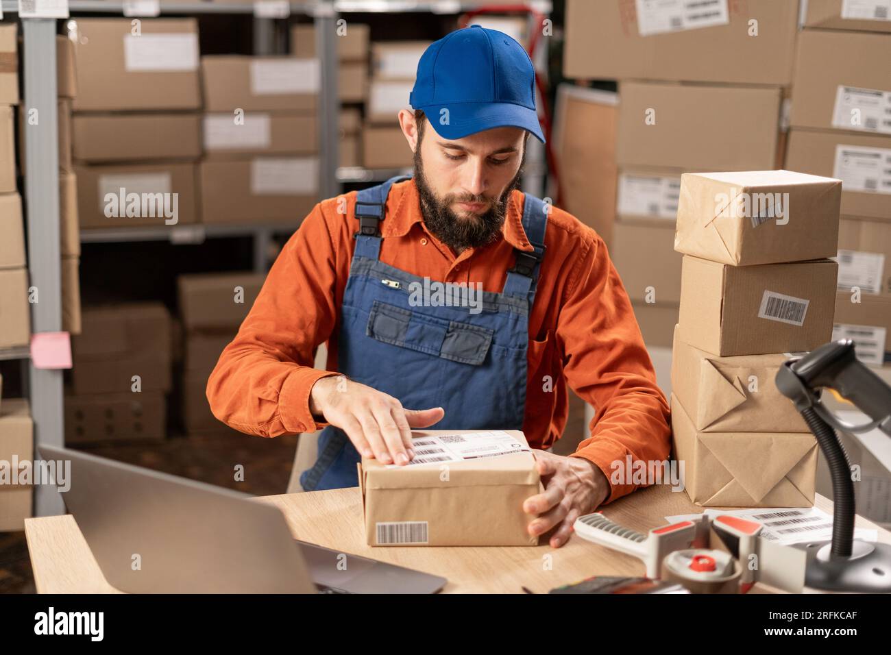 Warehouse worker applying shipping label on parcel boxes Stock Photo ...