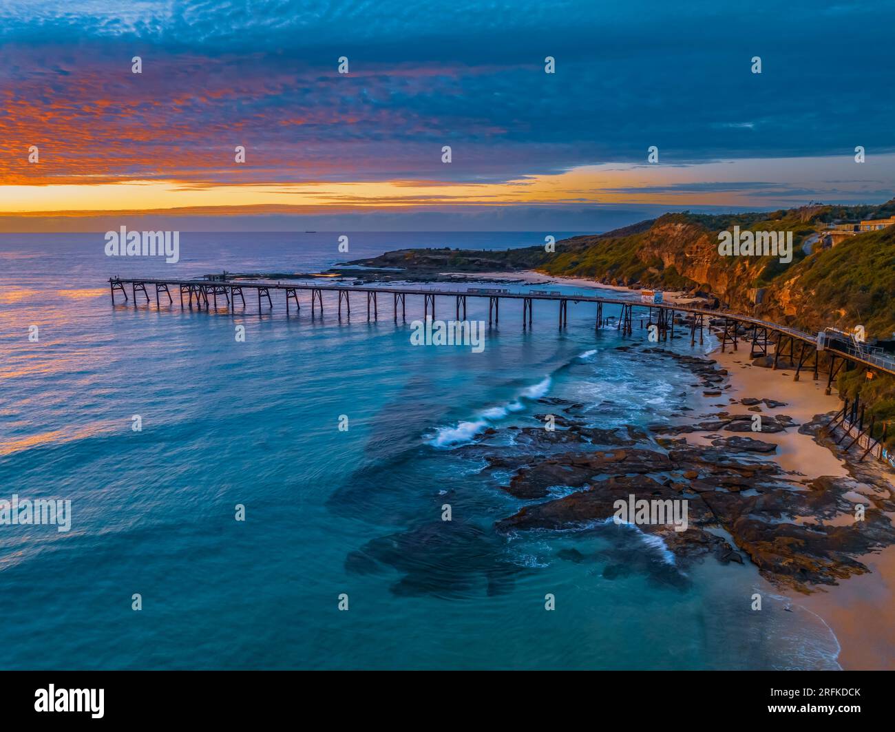 Sunrise seascape with cloud filled sky and the old coal loading jetty ...