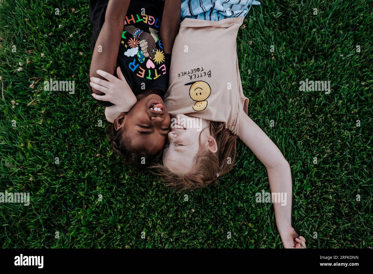 Two girls laying in grass making silly face Stock Photo - Alamy