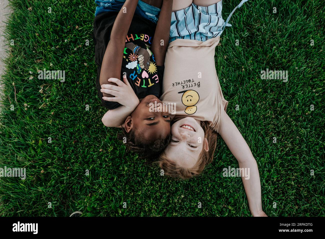 two girls laying in grass hugging and smiling Stock Photo - Alamy