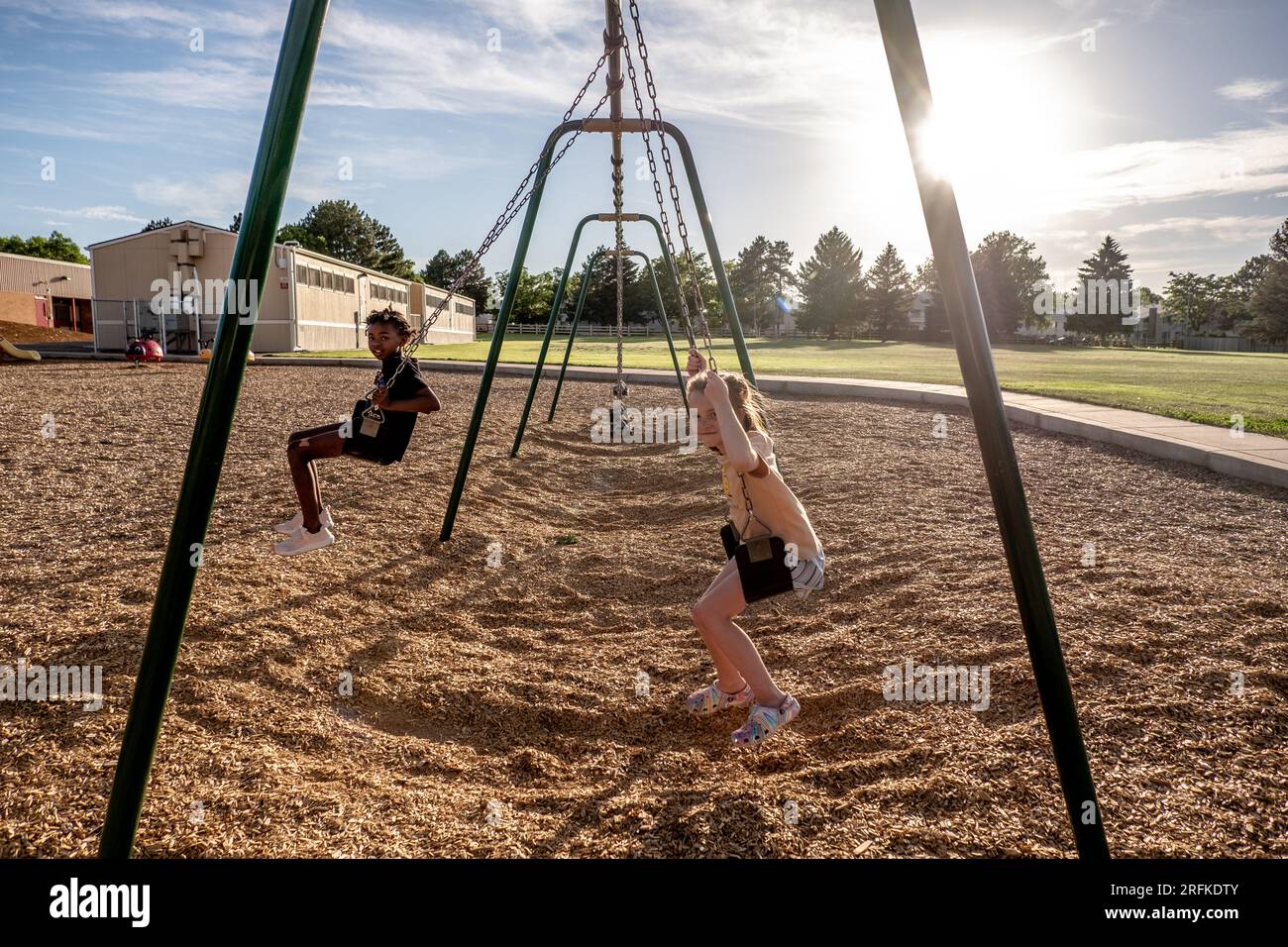 Happy young girls playing on swings at school Stock Photo - Alamy