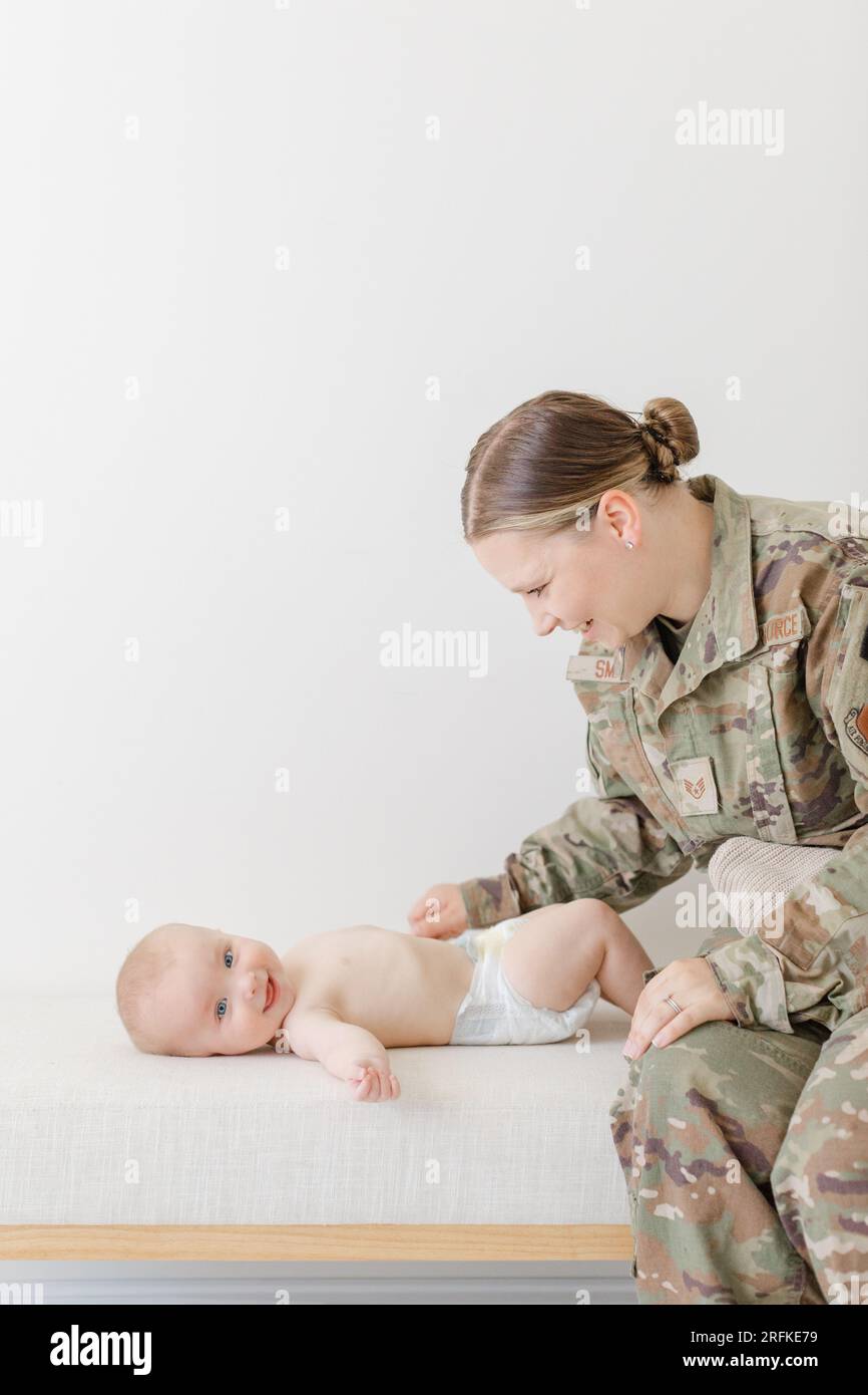 active duty military mom playing with baby as she changes his diaper ...
