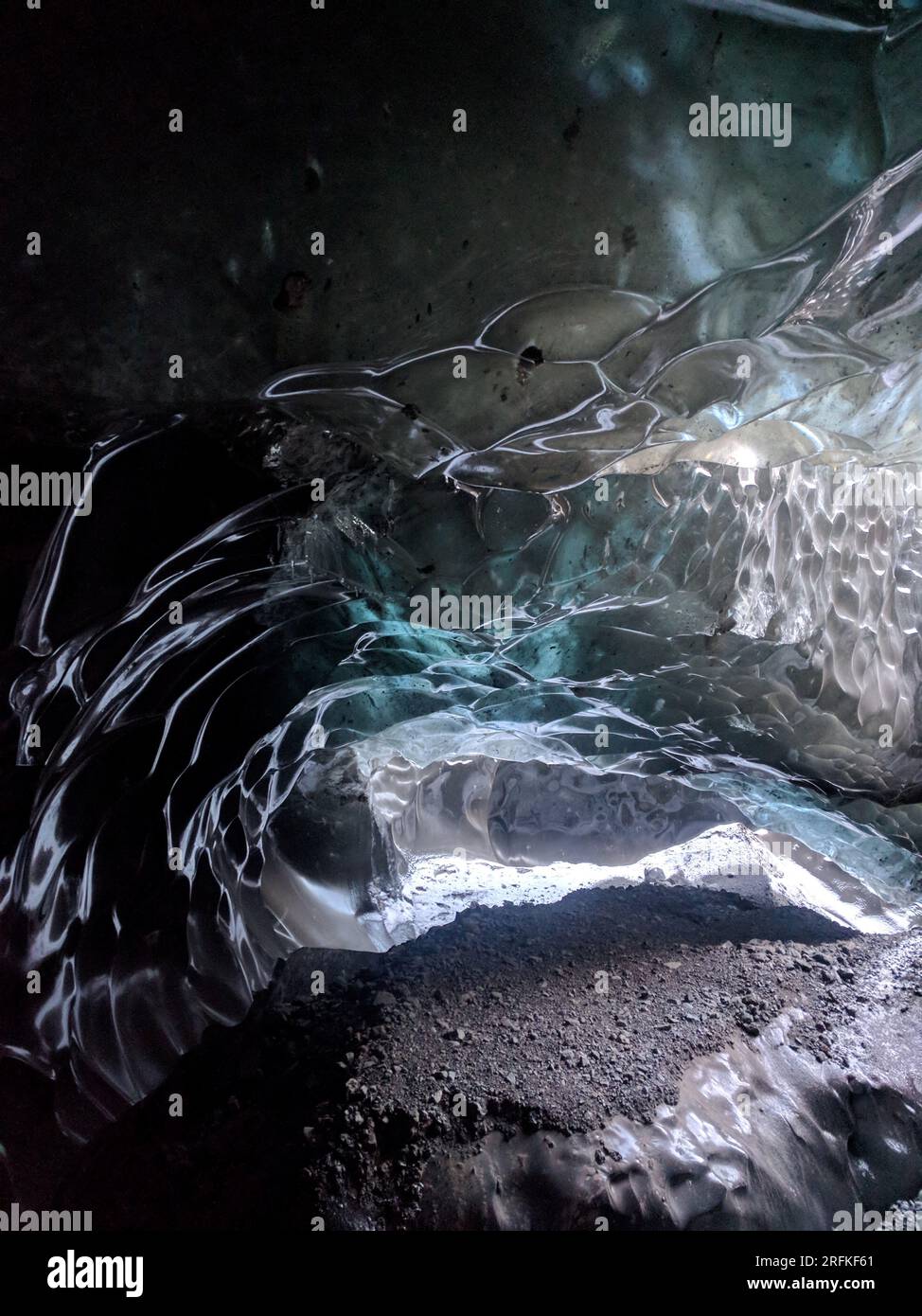 Interior of a blue glacial ice cave with pebble ground Stock Photo - Alamy