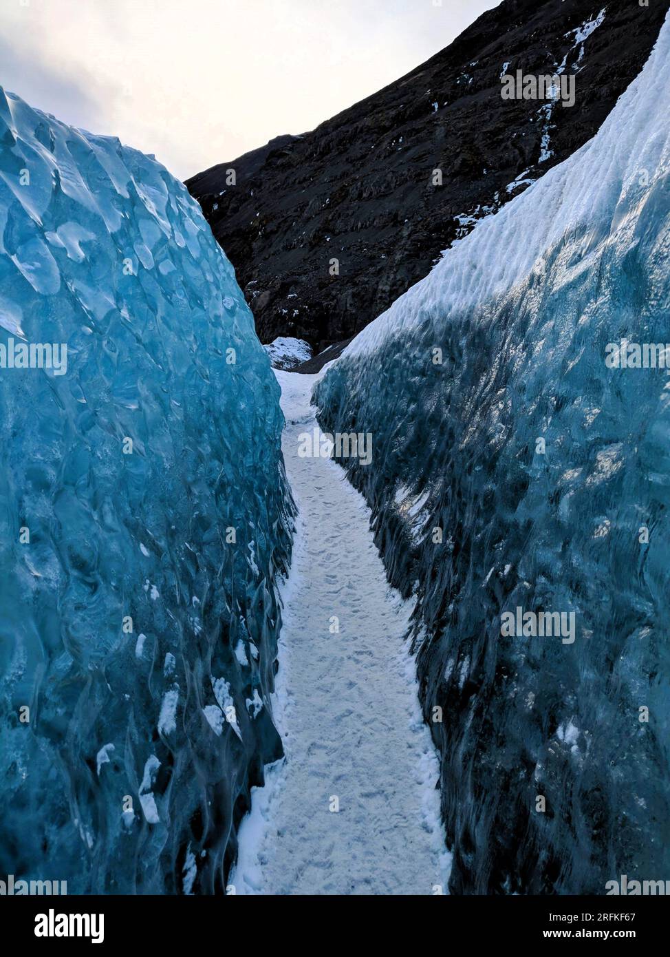 Snowy path through blue glacial ice with black craggy background Stock ...