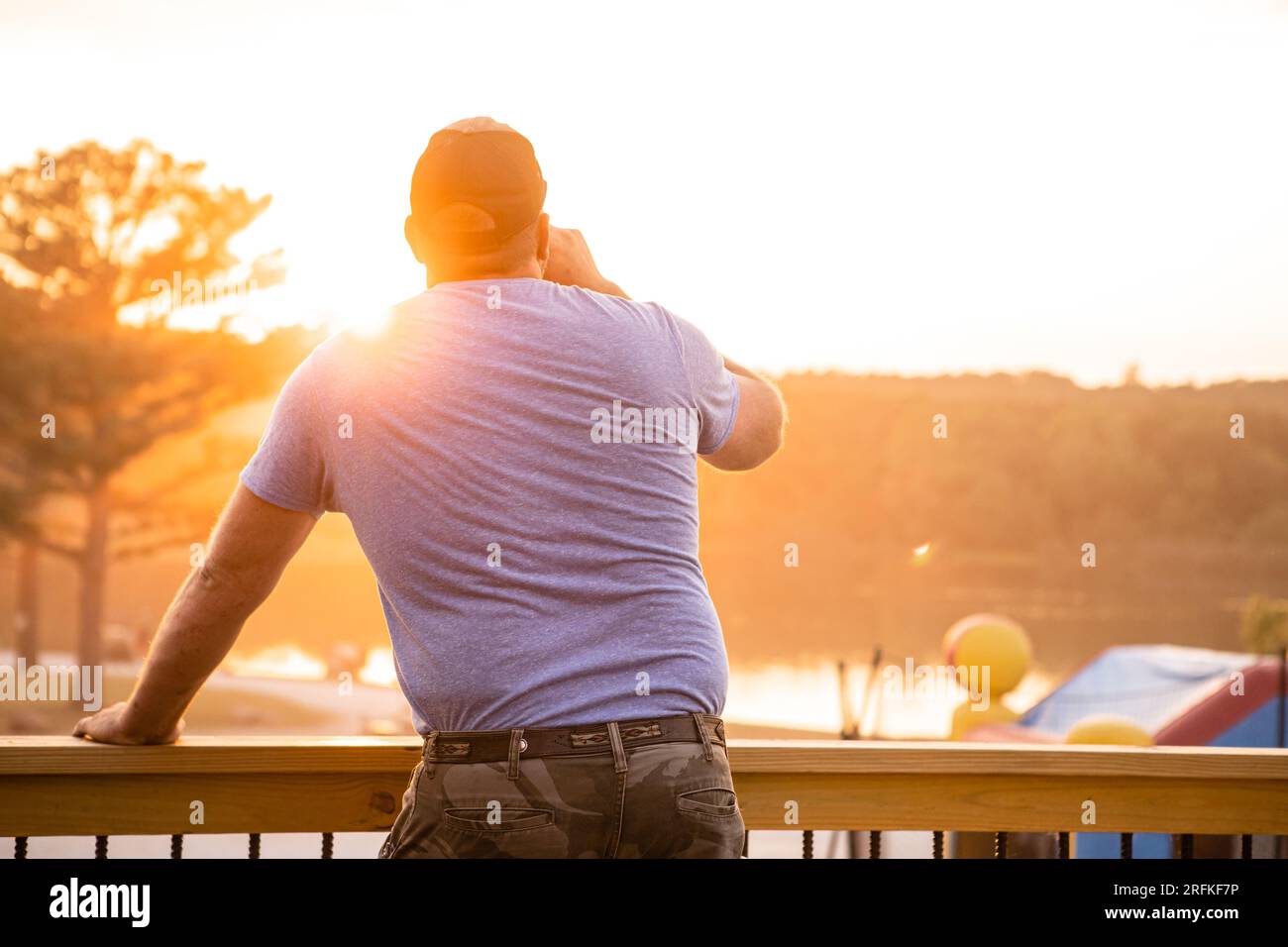 Man watching the sunset over lake while having a drink Stock Photo - Alamy