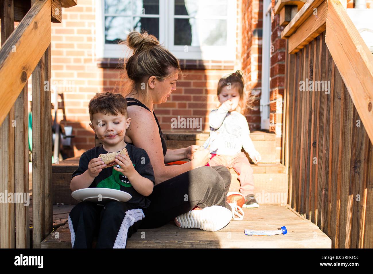 Mom and children eating a snack outside on sunny day Stock Photo - Alamy