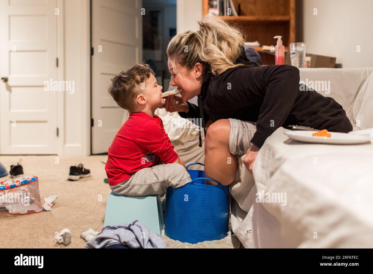 Goofy mom and son eating a snack together inside Stock Photo - Alamy