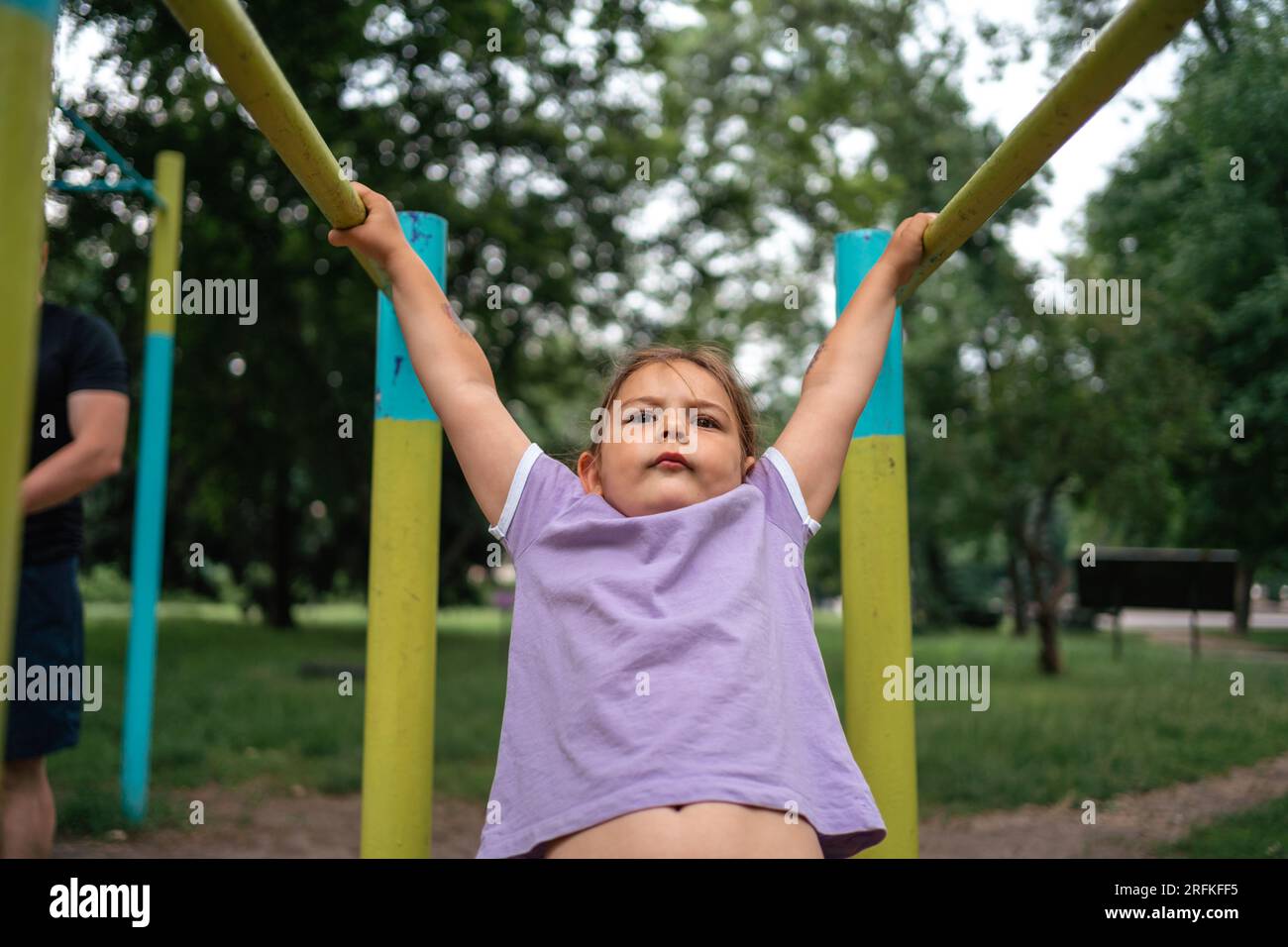 Father with child girl doing pull-ups on workout outdoor area. Healthy ...
