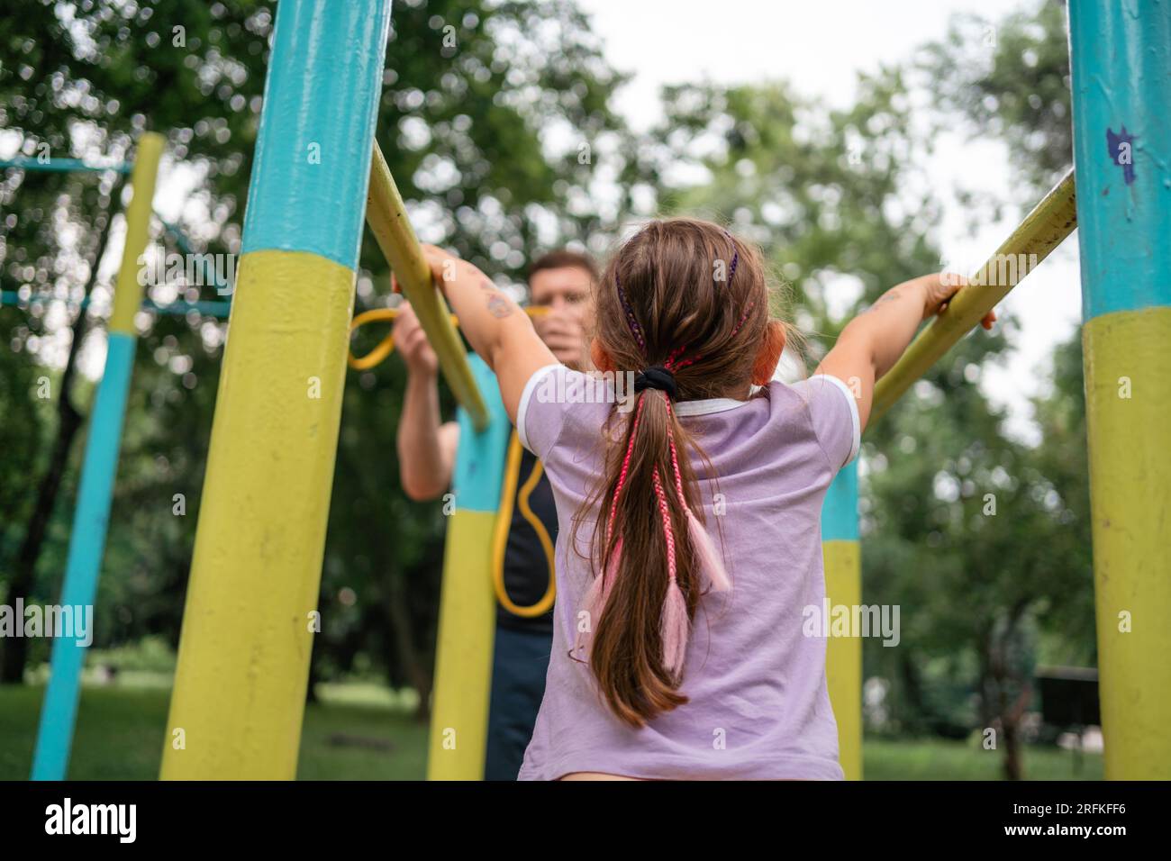 Father with child girl doing pull-ups on workout outdoor area. Healthy ...