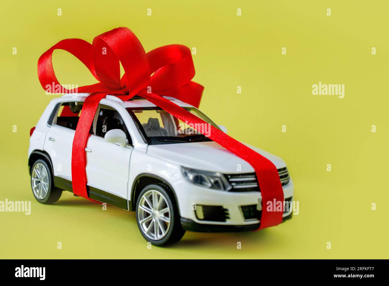 White model car with bow on a yellow background. Car as gift, surprise ...