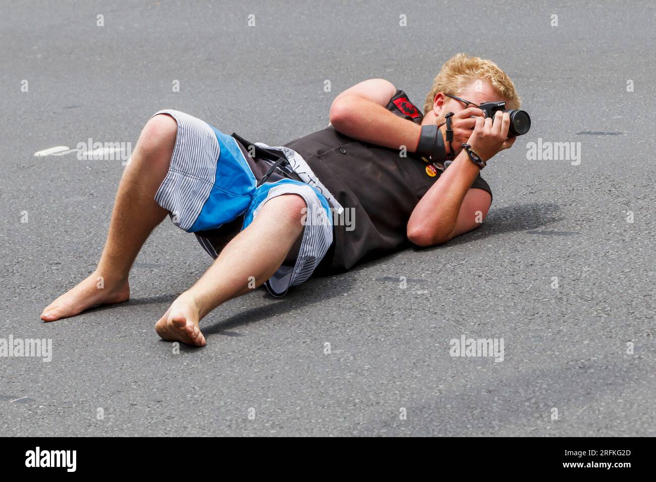 A man with a camera lays on the ground taking a photograph Stock Photo ...