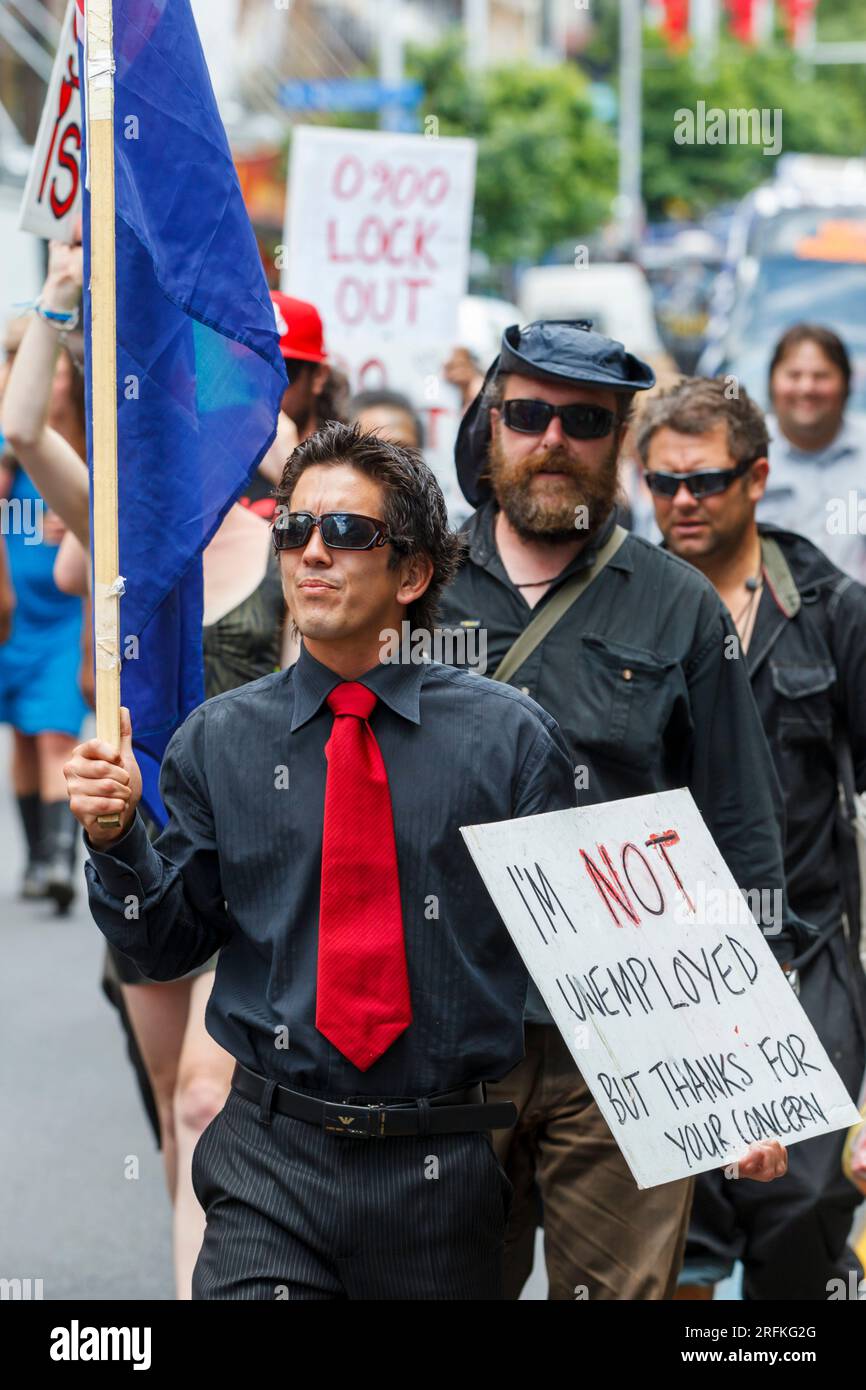 A protestor marches along the street holding a flag and banner followed ...