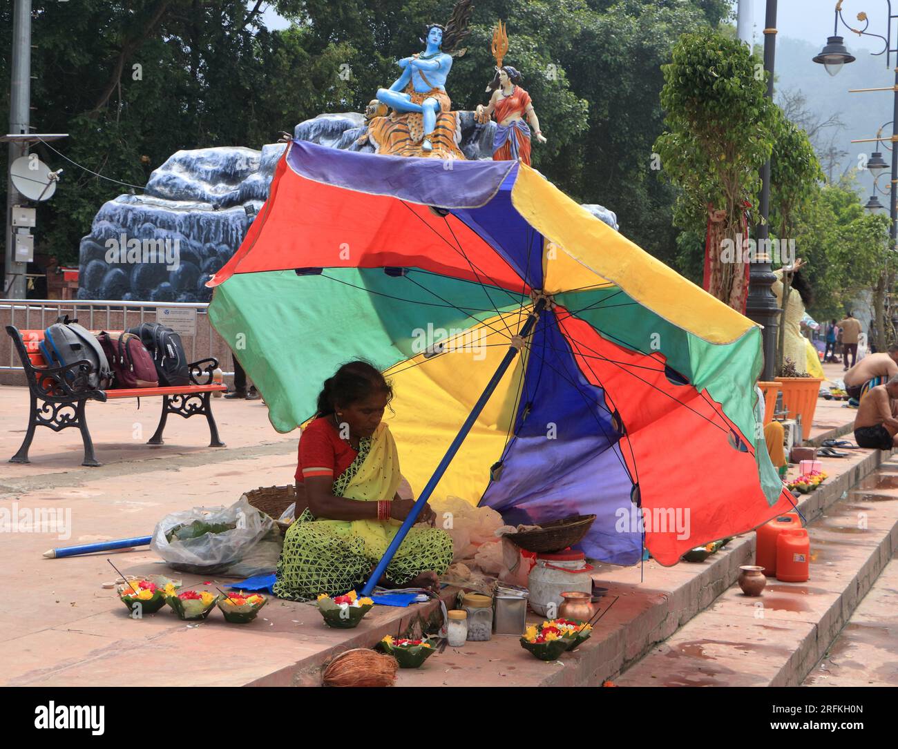 A poor woman selling puja items at Triveni Ghat, Rishikesh, holding an ...