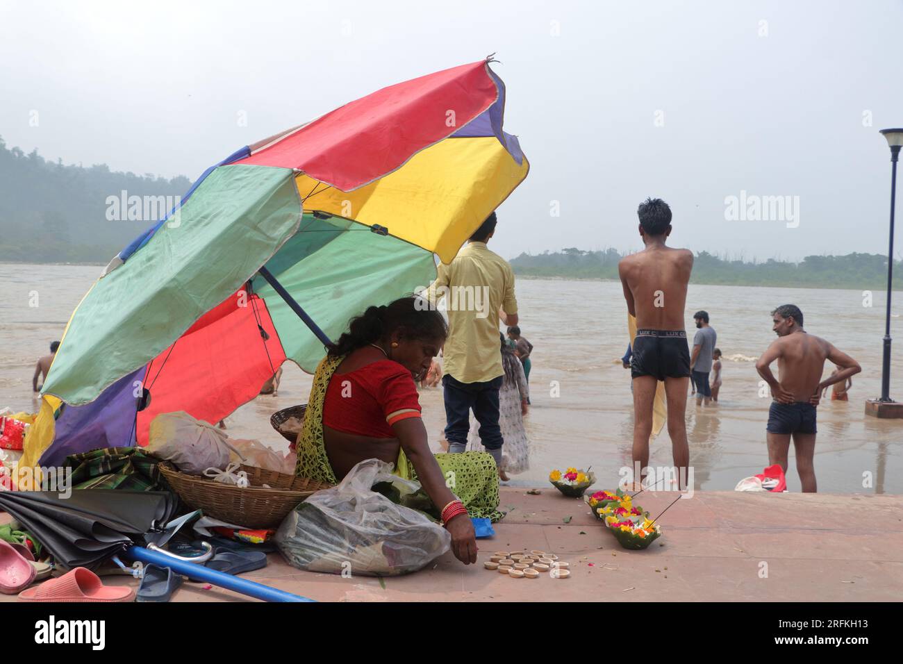 A poor woman selling puja items at Triveni Ghat, Rishikesh, holding an ...