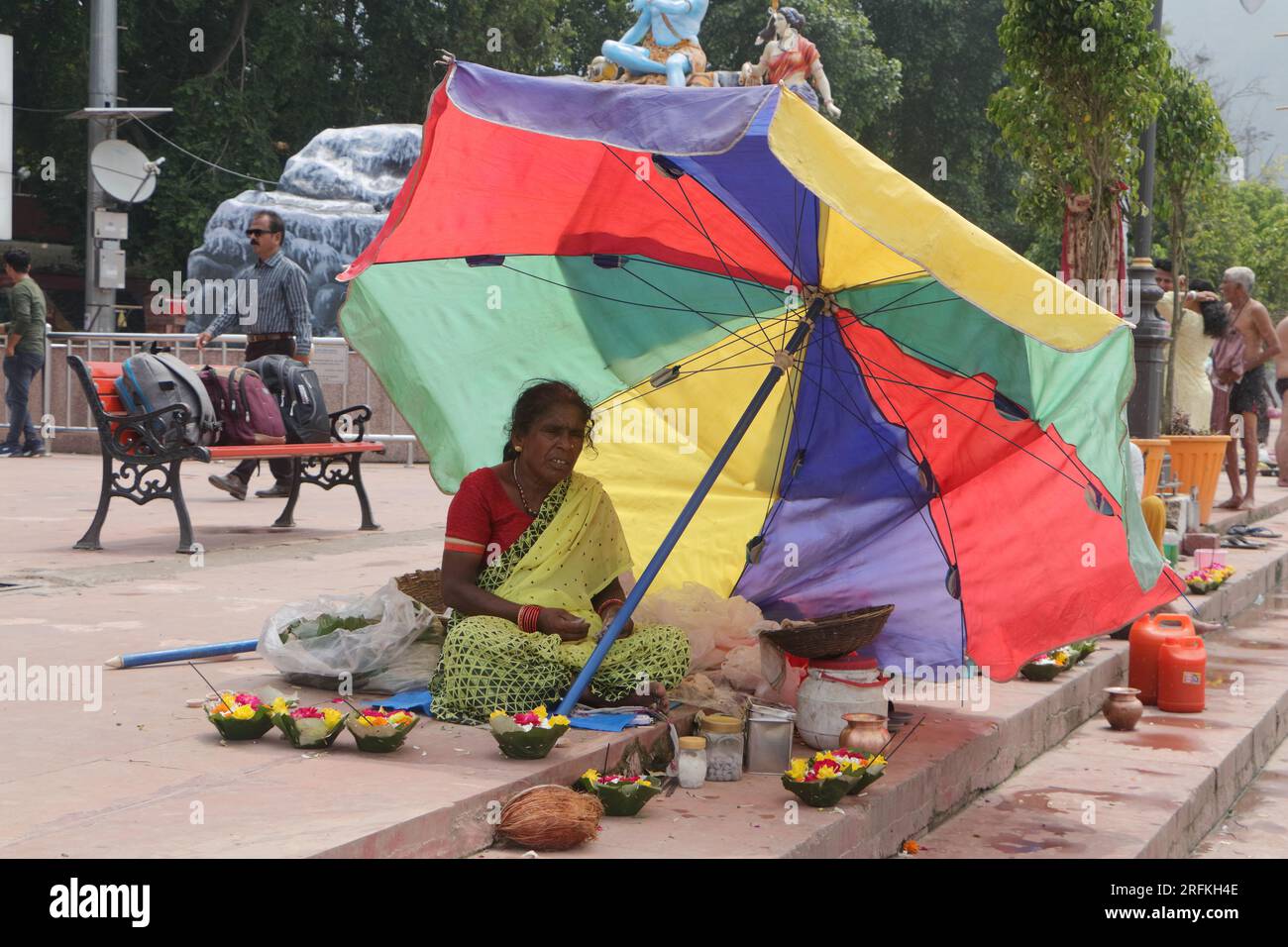 A poor woman selling puja items at Triveni Ghat, Rishikesh, holding an ...