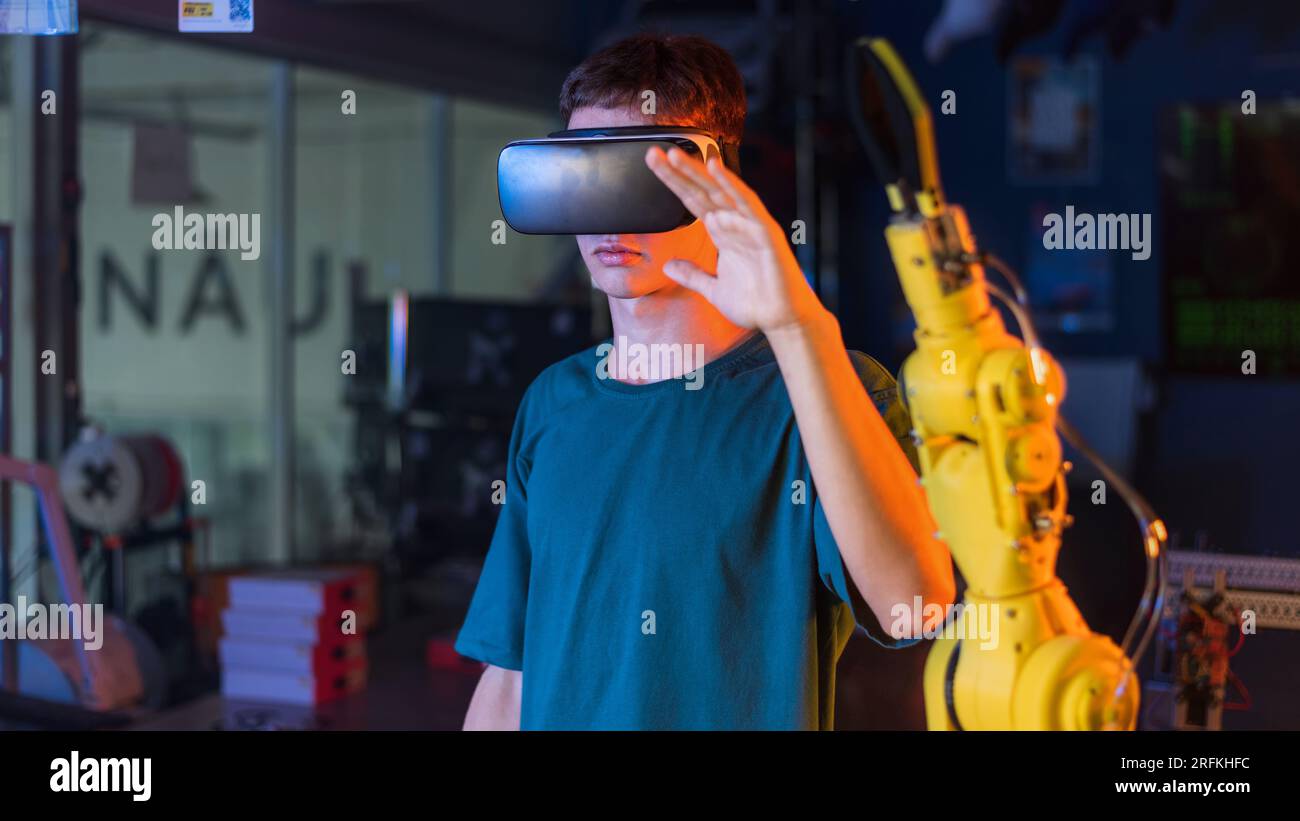 Teen doing experiments in robotics in a laboratory. Boy in VR headset ...