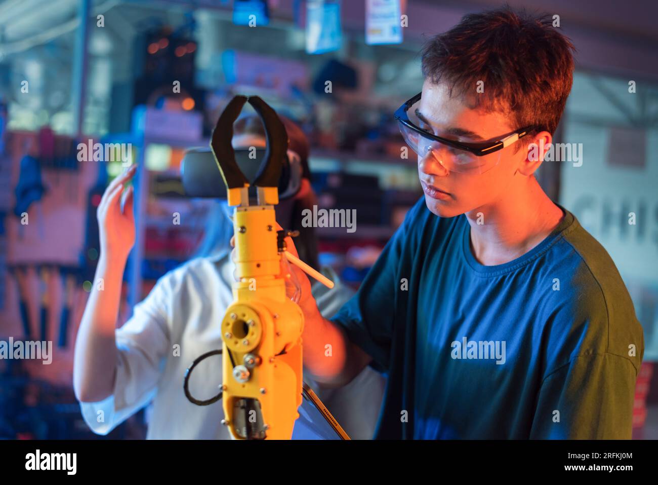 Teens doing experiments in robotics in a laboratory. Boy in protective ...