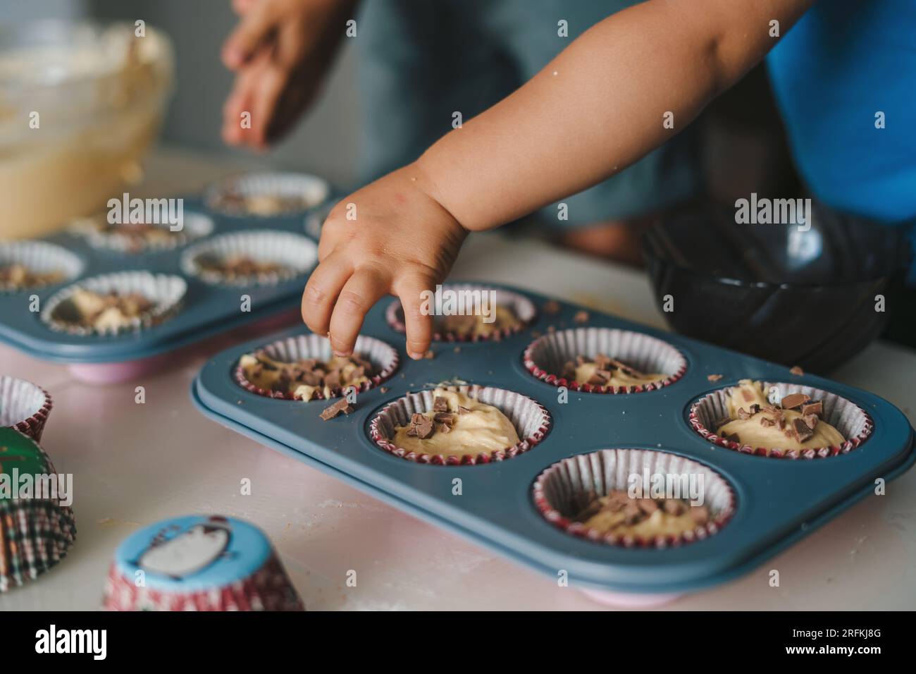 Little baby's hand sprinkling Chocolate on ripe cupcakes. Family having ...