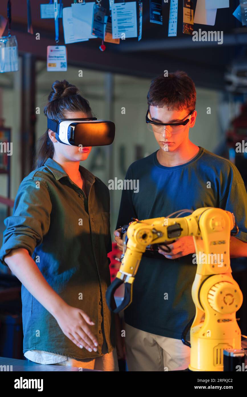 Teens doing experiments in robotics in a laboratory. Boy in protective ...