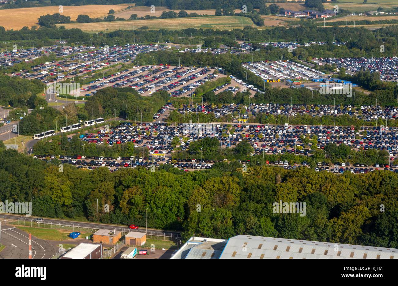 Oblique aerial view through plane window of cars in crowded car parks ...