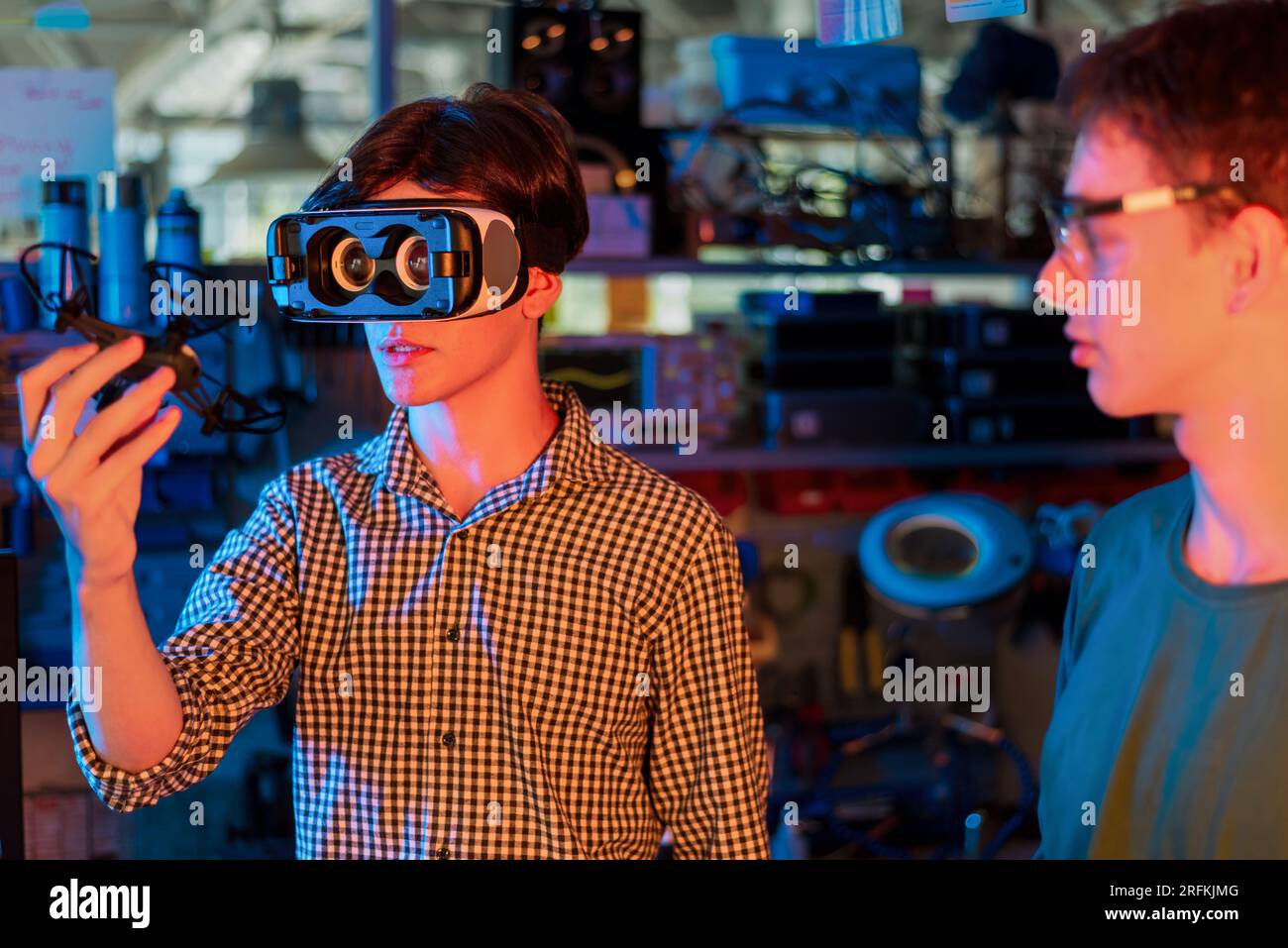 Teens doing experiments in robotics in a laboratory. Boy in VR headset ...