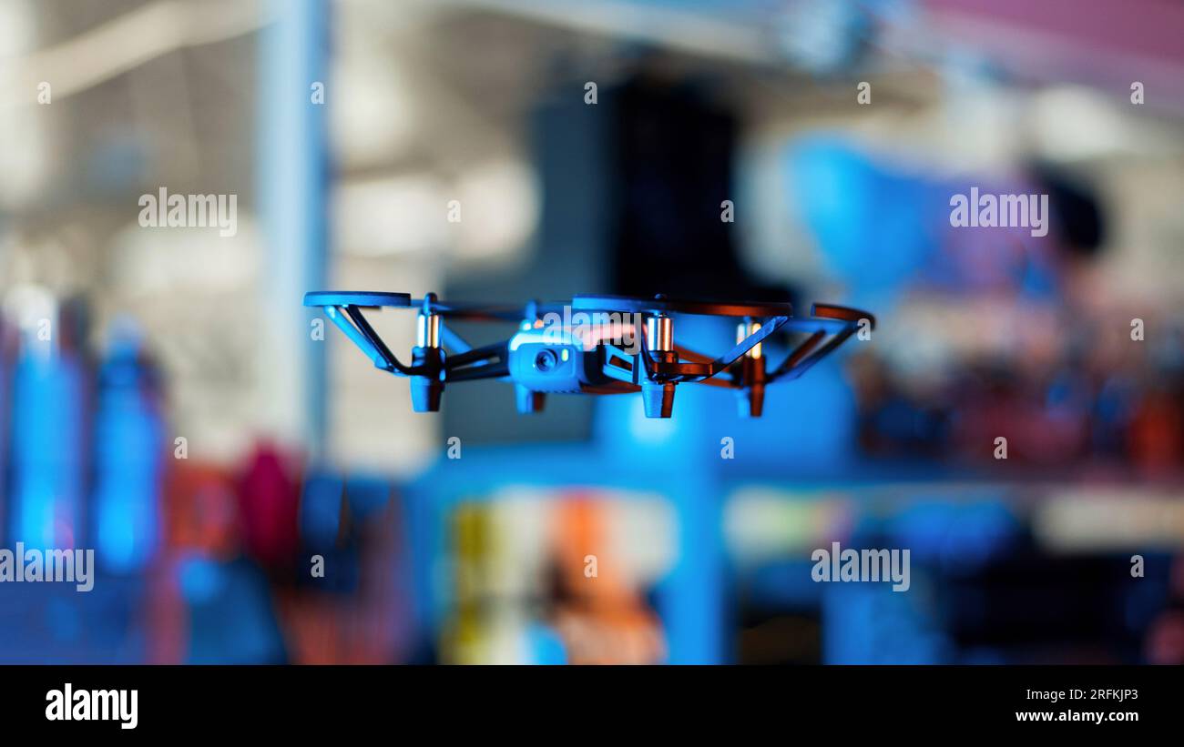 Close view of a small flying drone with blurred background. Red and ...