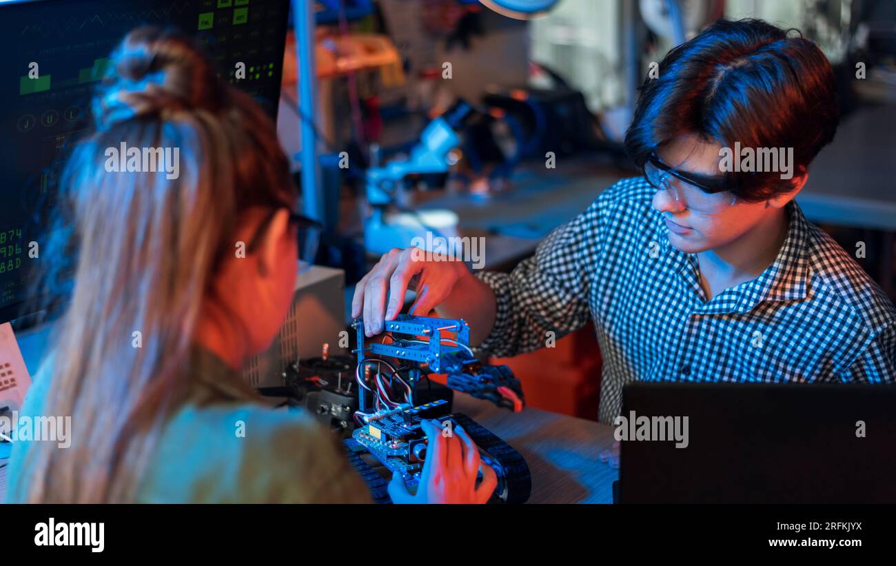 Teens doing experiments in robotics in a laboratory. Boy and girl in ...